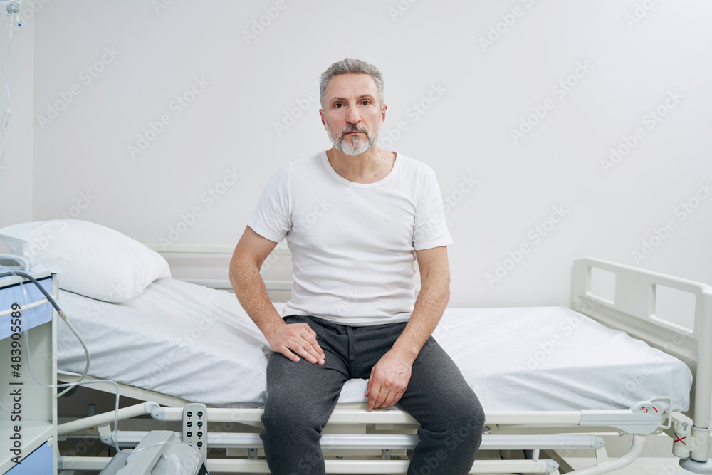 Sad female patient seated alone on hospital bed staring ahead Stock ...