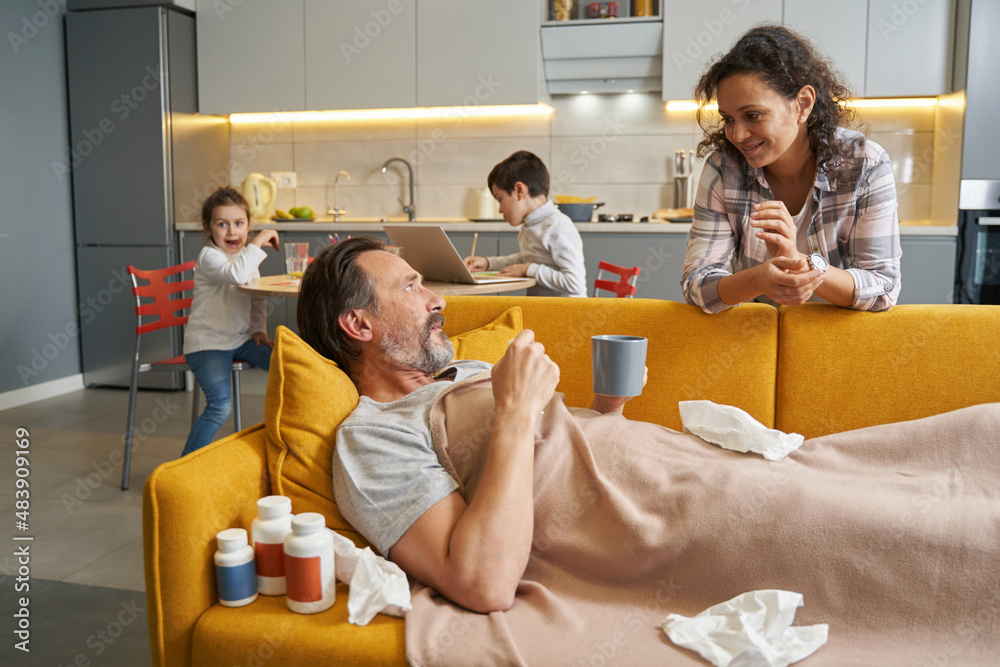 Sick person looking at female while drinking tea Stock Photo | Adobe Stock