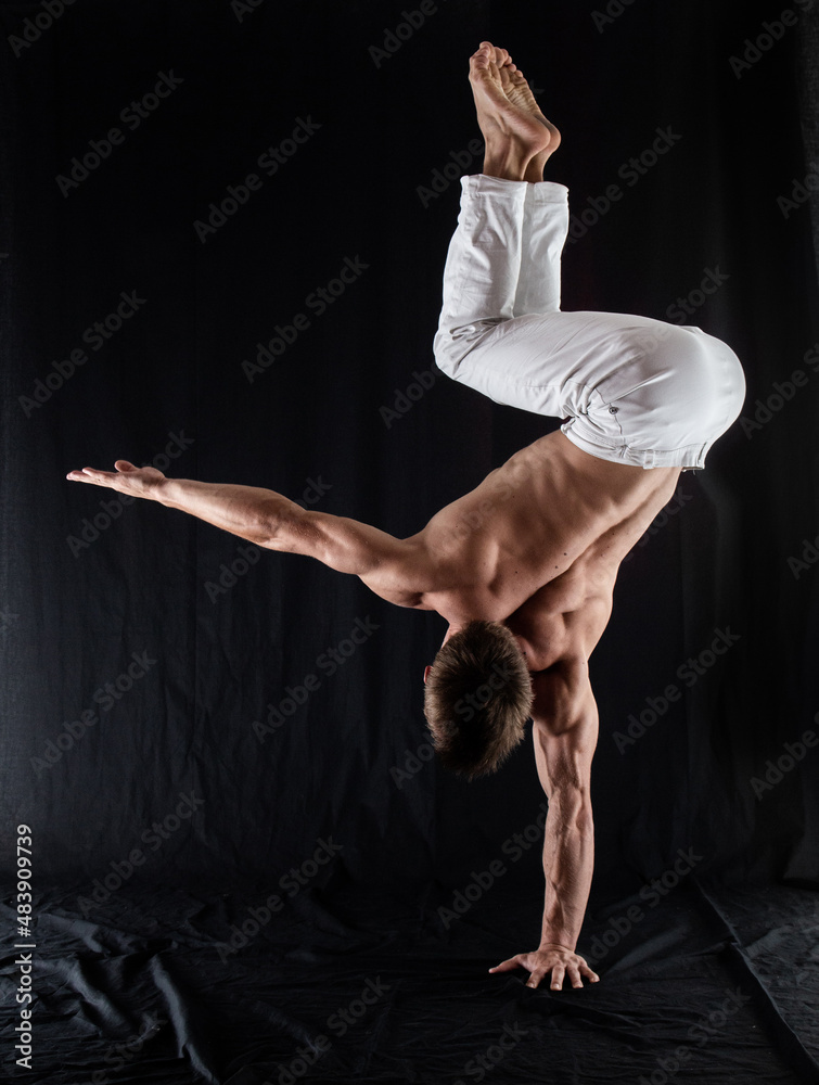 circus artist keeps balance on one hand isolated on a black background ...