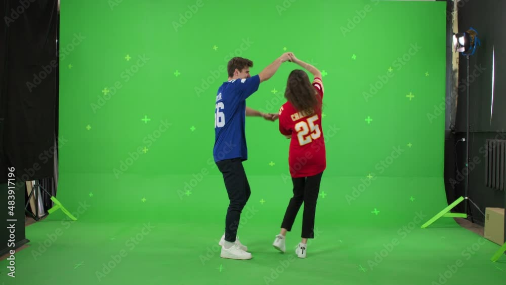 A young couple dancing making content on a green screen background. A ...