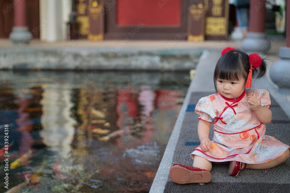 Asia Chinese baby girl in chinese tradition cloth sit at fish pond use ...