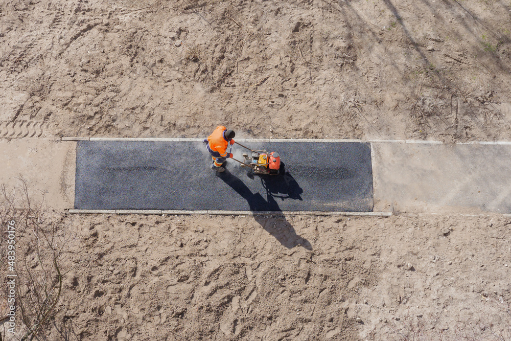 New asphalt construction worker laying road surface on walkway work ...