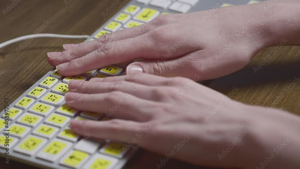Close-up of a computer keyboard with braille. A blind girl is typing ...