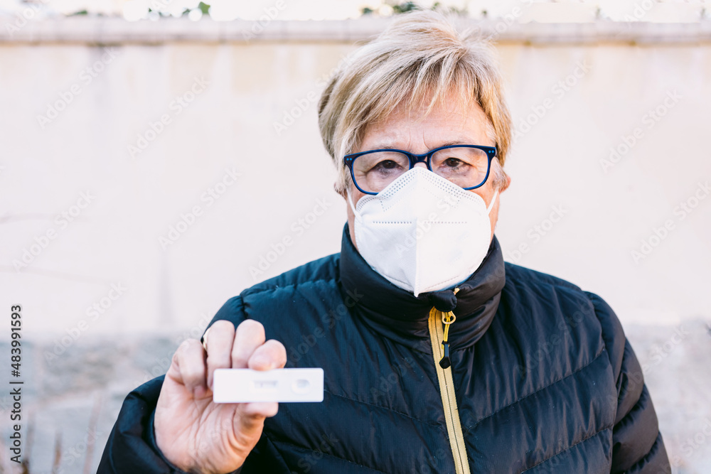 Elderly lady on the street, wearing a white mask, with a negative ...