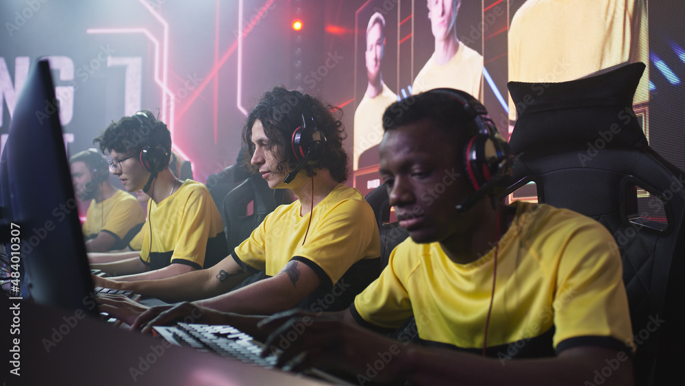 Concentrated esportsman gamer speaking with teammates and playing video ...