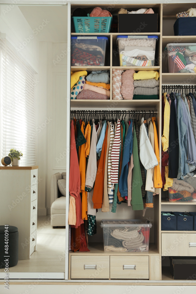 Wardrobe closet with different stylish clothes and home stuff in room ...
