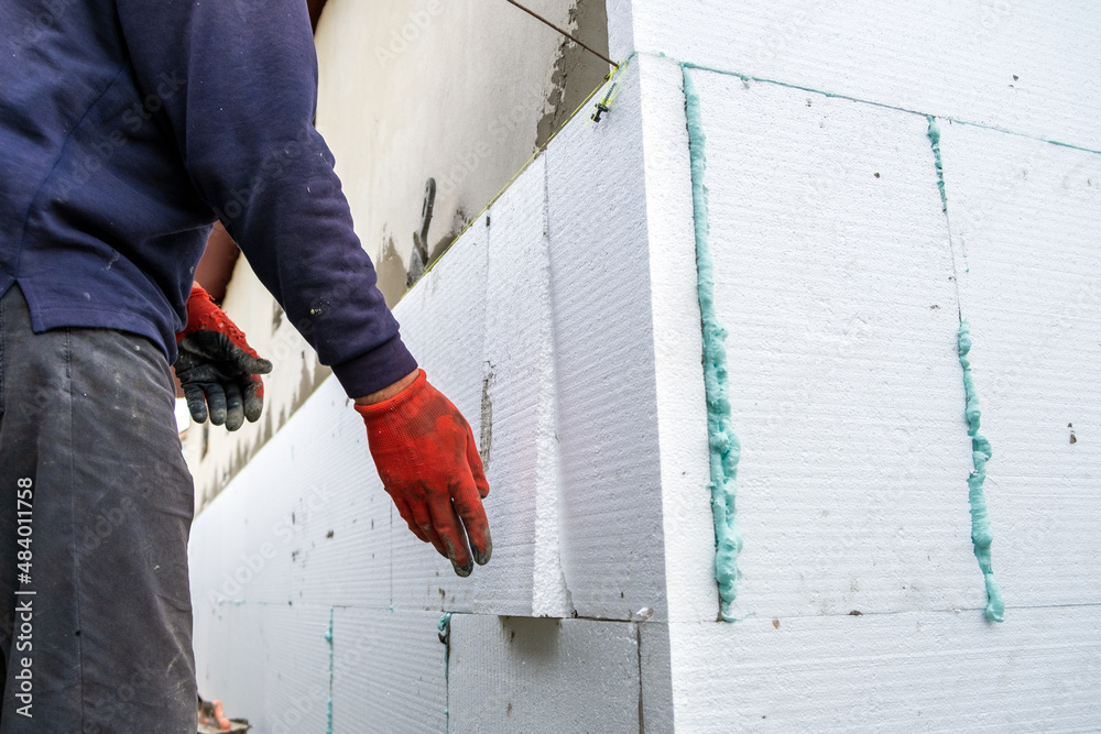 Construction worker installing styrofoam insulation sheets on house ...