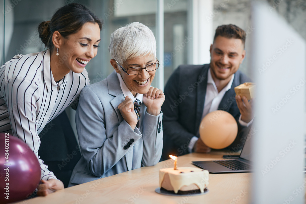 Happy senior CEO making a wish while blowing candle on Birthday cake ...