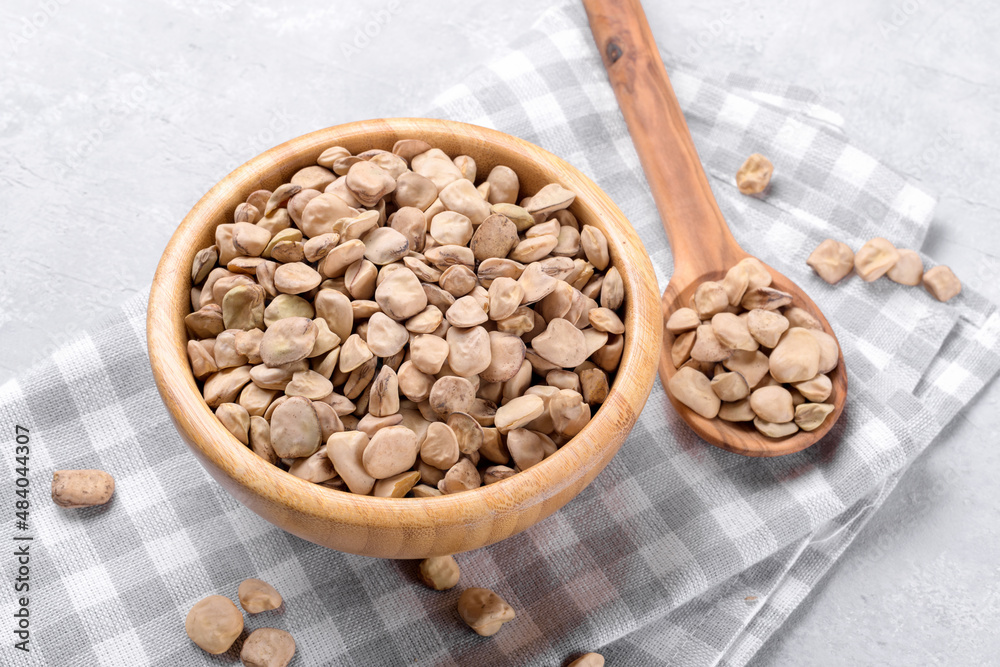 Cicerchia or indian pea in a wooden bowl and spoon with napkin on grey ...