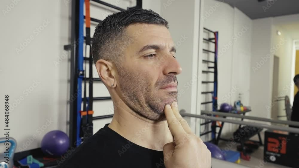 Close-up as a man demonstrates how to stretch the back of the neck with ...