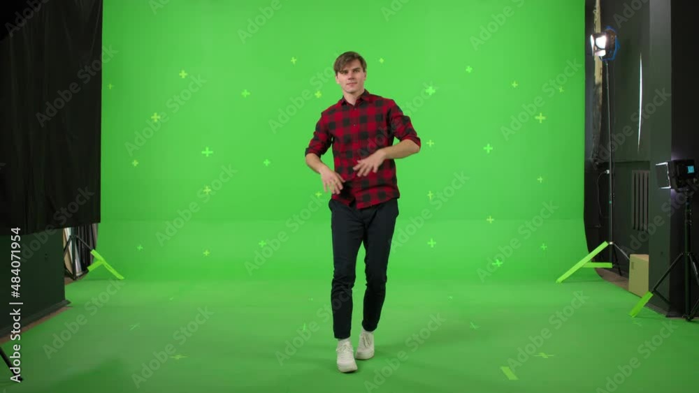 A young man dancing on a green screen background. Attractive guy makes ...