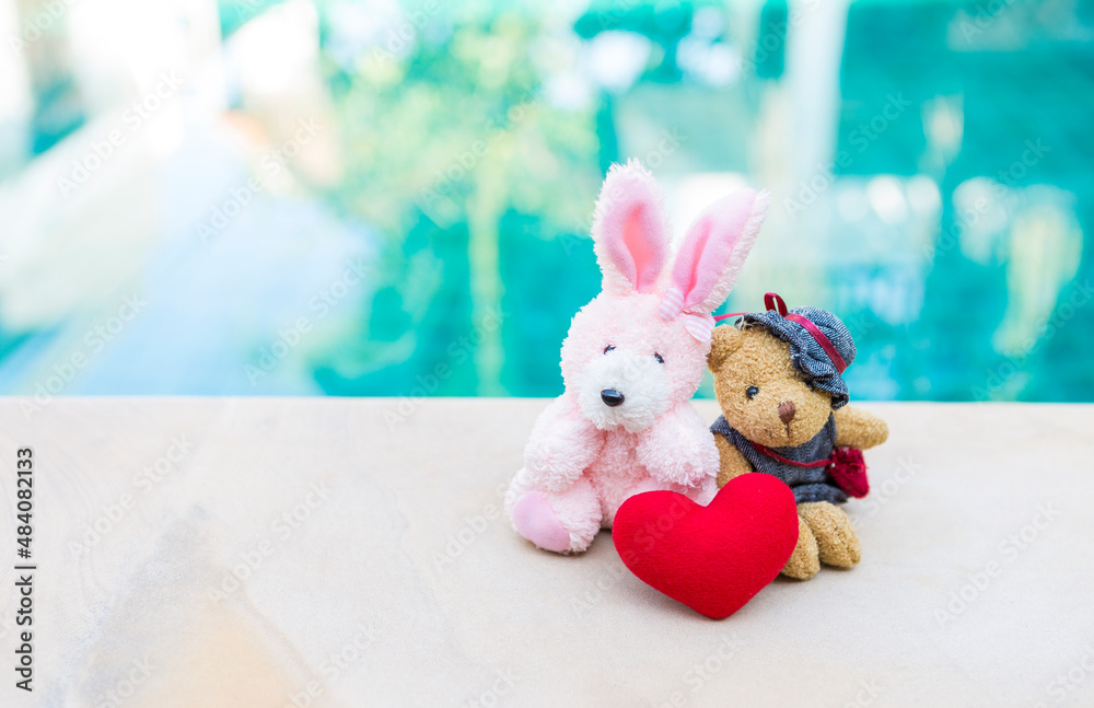 Pink rabbit and little teddy bear with red heart sitting on swimming ...