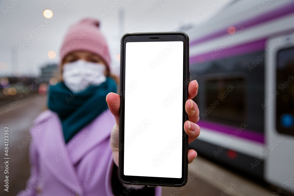 Smart phone with white screen in hand. Woman in protective mask showing ...