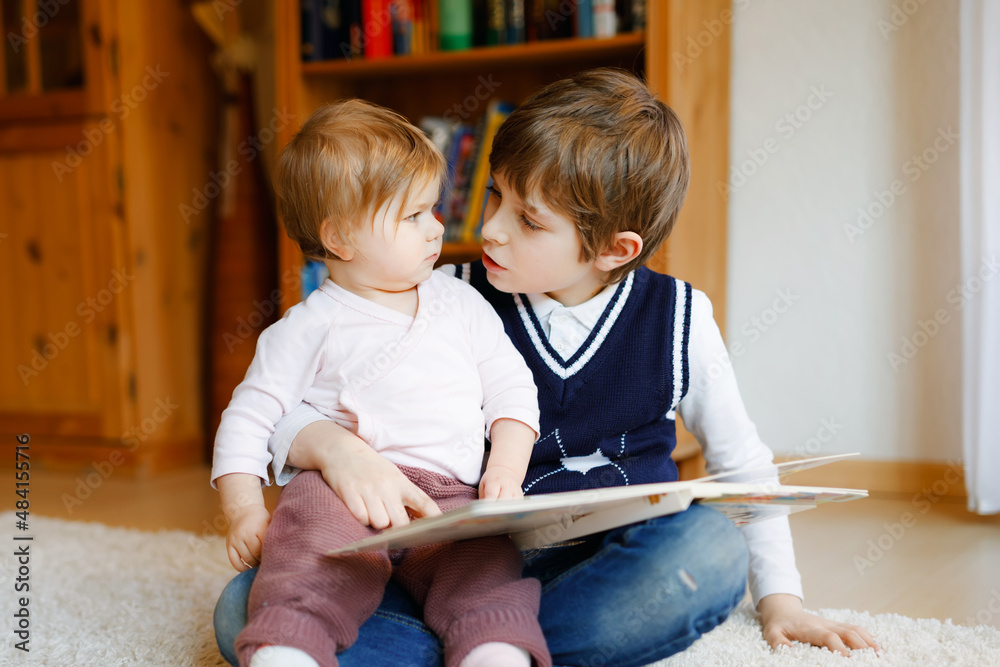 School kid boy reading book for little toddler baby girl, Two siblings ...