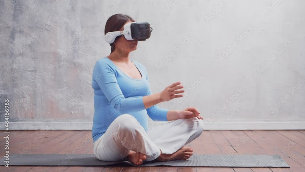 Young pregnant woman in VR helmet. She is preparing for the birth of a ...