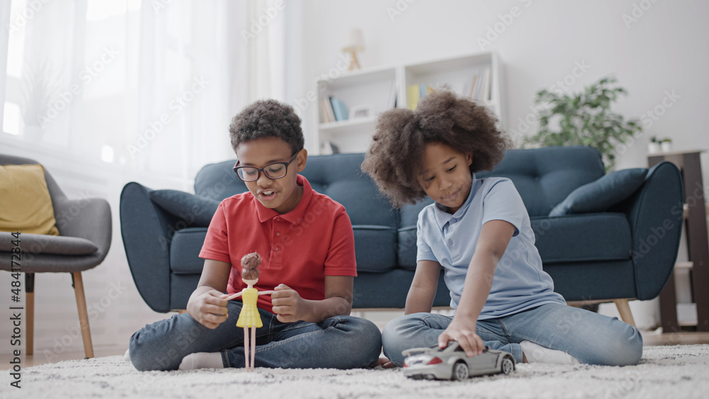 Curious little boy playing with a doll and his sister playing with a ...