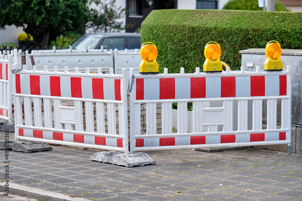 Street barriers with yellow warning lights standing in front of a ...