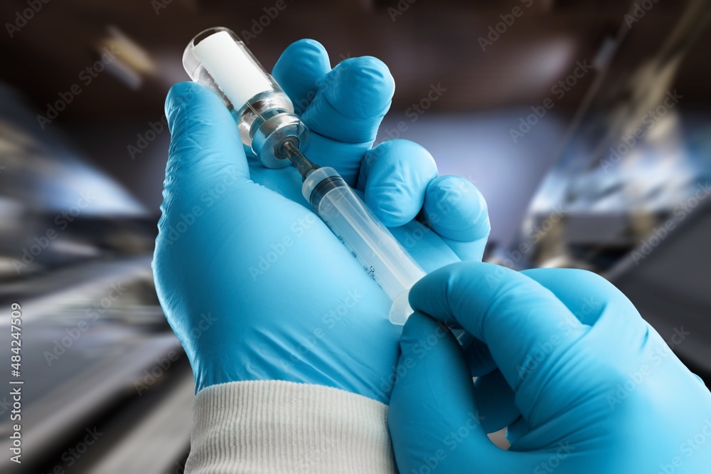 Doctor or scientist filling a syringe with liquid vaccines booster ...