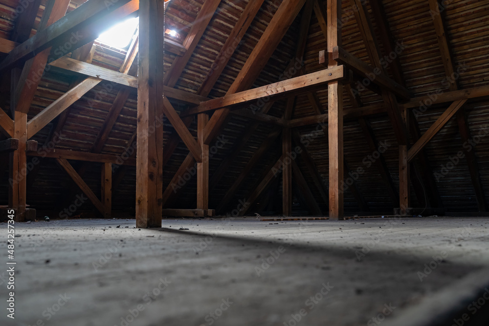 Old dusty attic of a building. Empty space lit by a roof window. Wooden ...