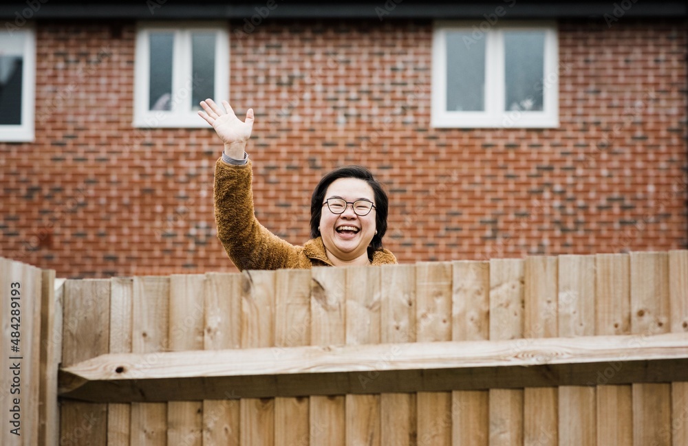 happy friendly neighbour waving over a garden fence saying hello Stock ...