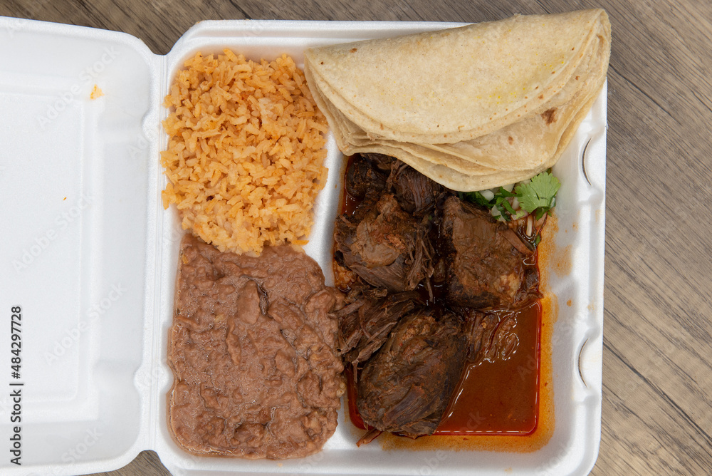 Overhead view of hearty take out order of birria stew meat served to ...