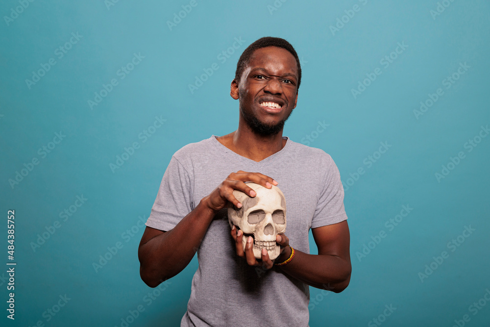 Portrait of male model holding skull from human skeleton to study ...