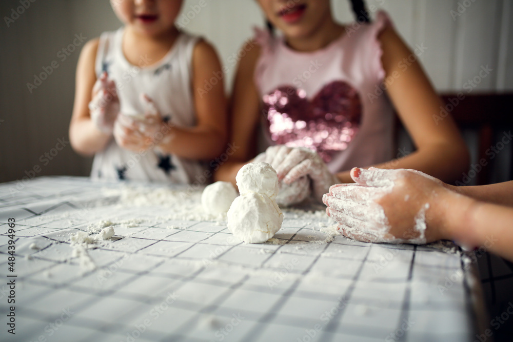 Funny children play with artificial snow at home in the kitchen ...