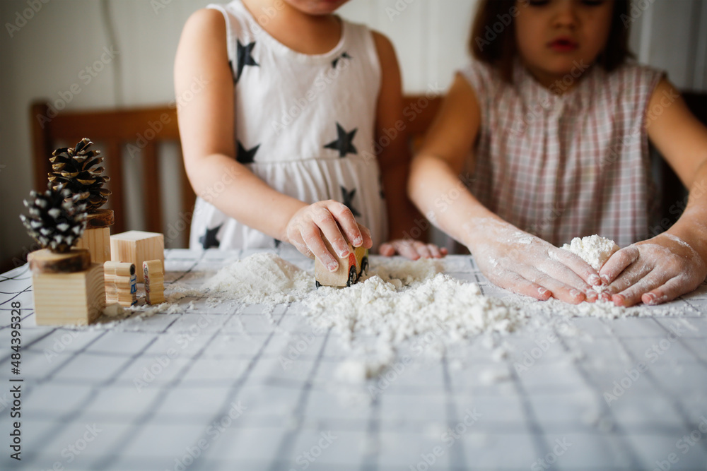 Funny children play with artificial snow at home in the kitchen ...