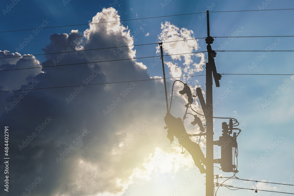 The silhouette of power lineman replacing a transformer and hotline ...