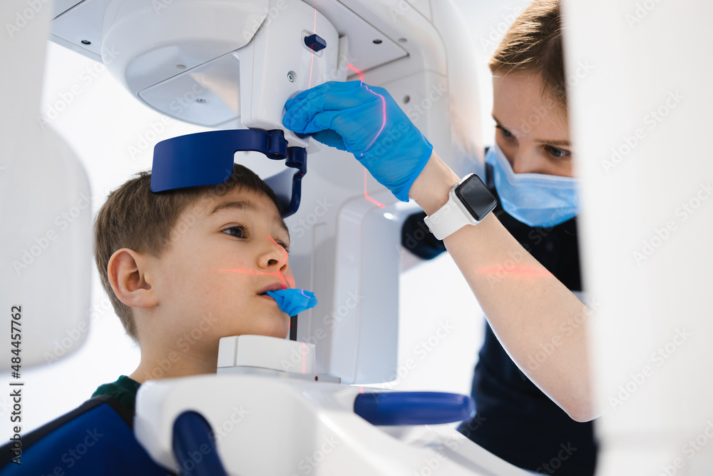 Dentist taking panoramic teeth radiography to a little boy using modern ...