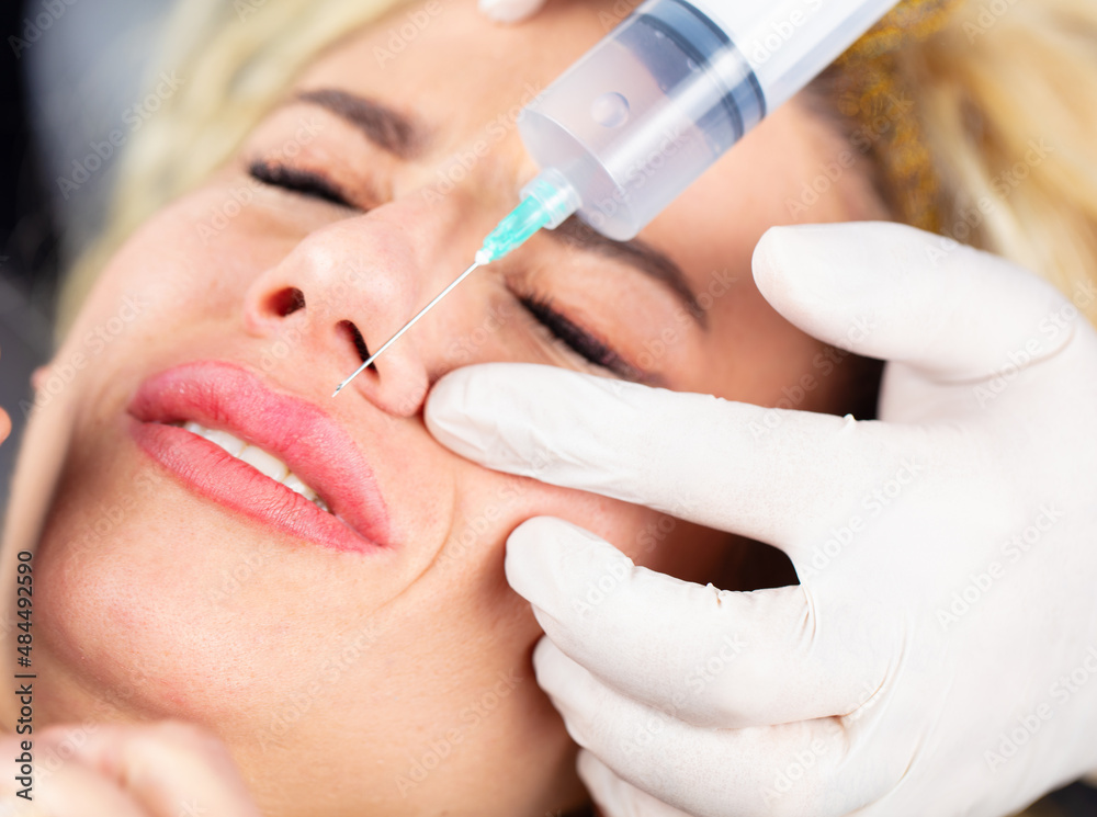 Young lady getting botox injection for bigger, fuller lips. The woman ...