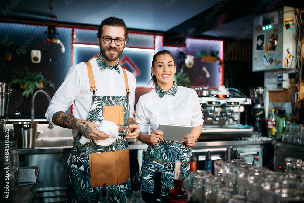 Happy bartender and his female coworker work behind bar counter and ...