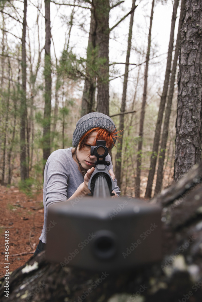 Looking down the barrel, beautiful and intense redhead sniper woman ...