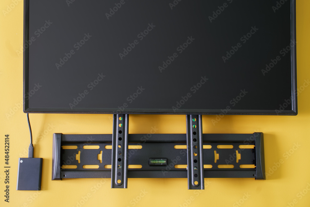 Metal TV wall mounting bracket, monitor screen and usb drive on yellow ...