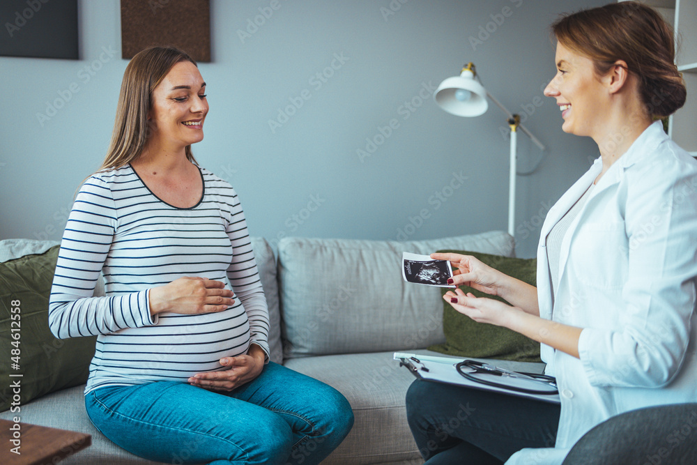 The doctor shows a sonographic picture of the baby while sitting on the ...