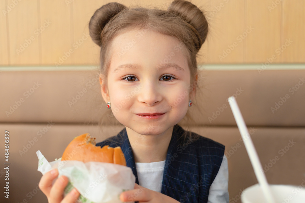 child in fast food restaurant. little girl with appetite eating ...
