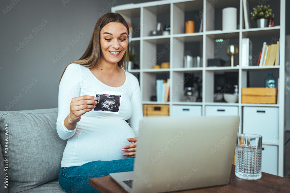 The selective focus of a cheerful pregnant woman who shows ultrasound ...