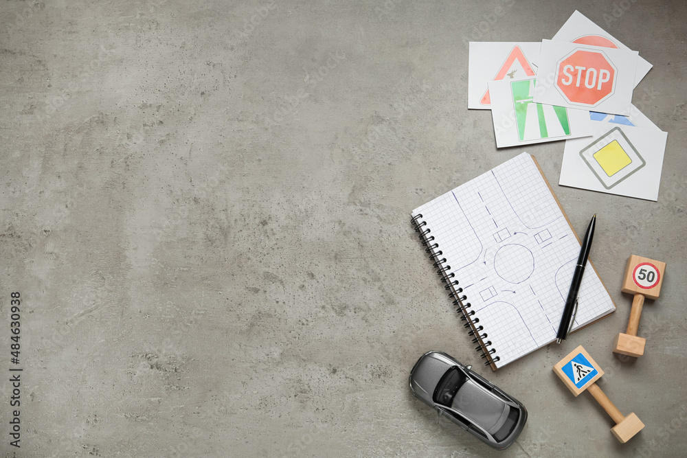Many different road signs, notebook and toy car on grey background ...