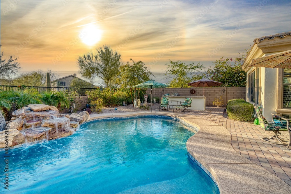 Luxury home pool at sunset with a waterfall Stock Photo | Adobe Stock