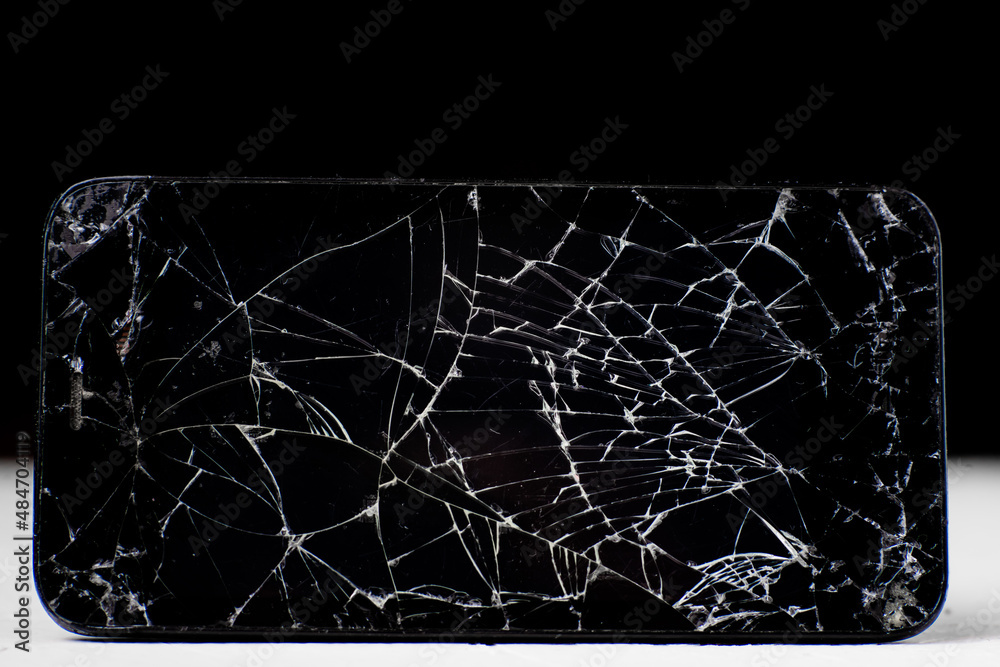 Broken mobile phone on a black and white background. Many cracks on the ...