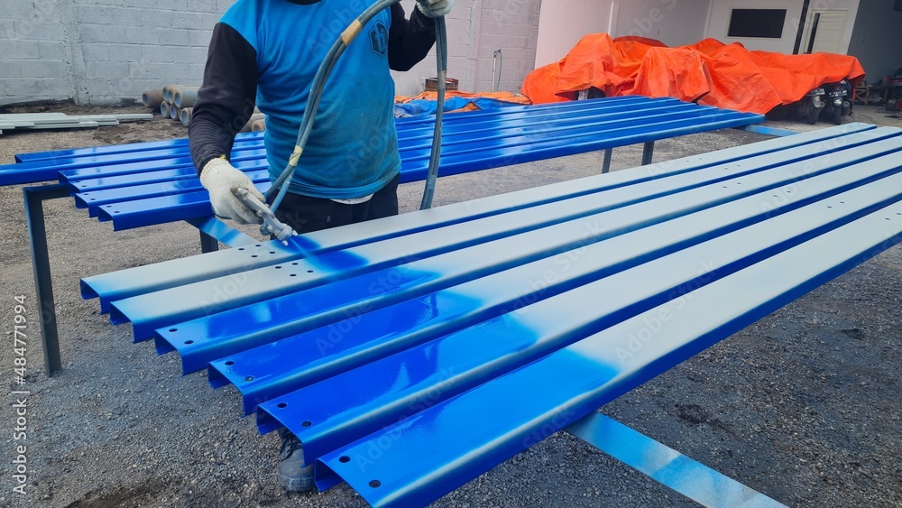 construction worker is painting steel construction with spray paint ...