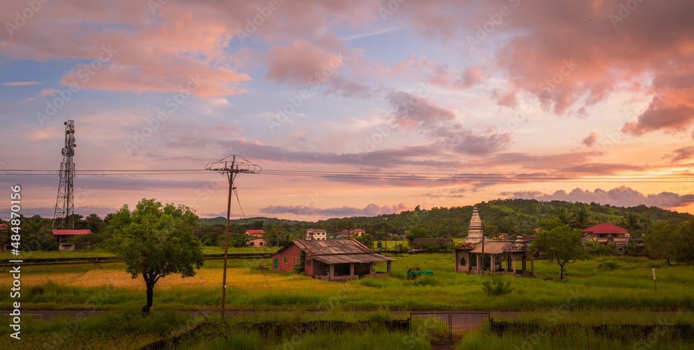 Traditional Indian village house and temple surrounded by green grass ...