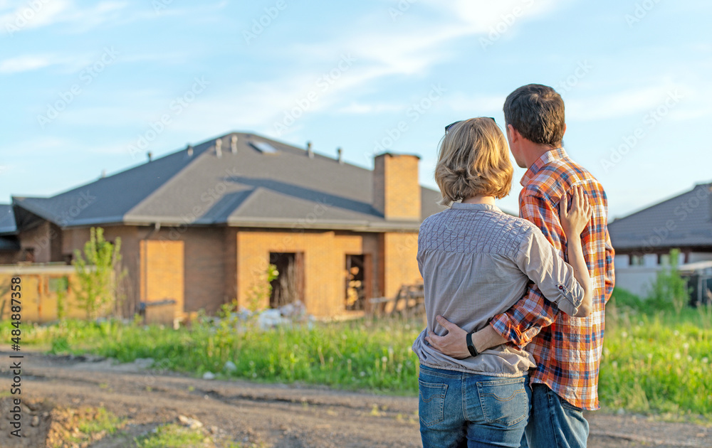 Back view of happy family is standing near their new modern house and ...