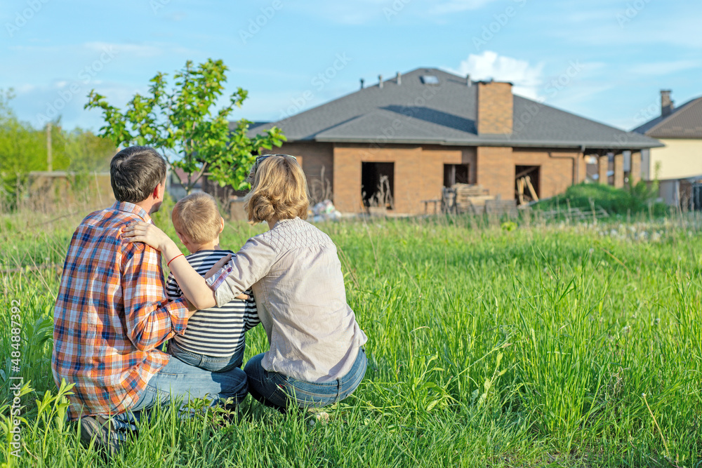 Back view of happy family is standing near their new modern house and ...