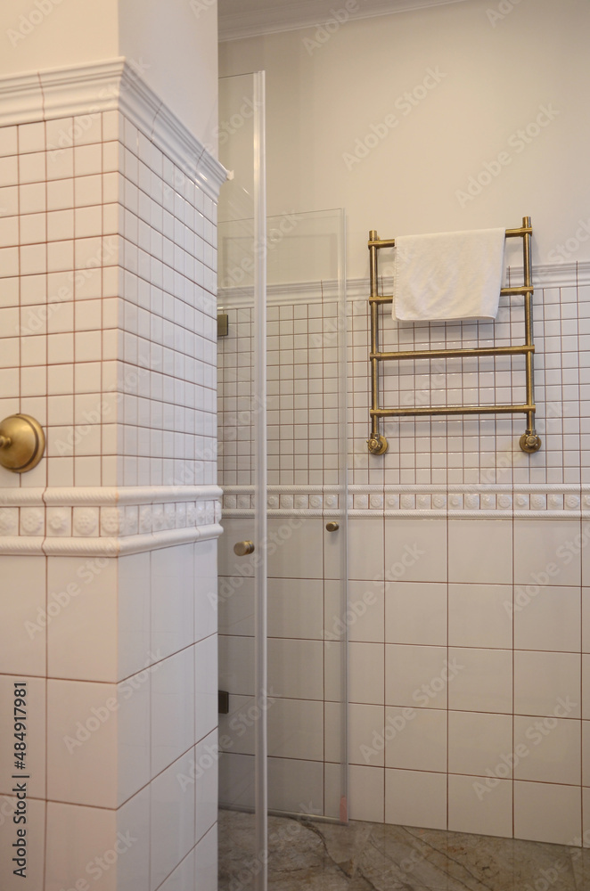 beautiful shower room with white tiles and bronze faucet. Glass shower ...