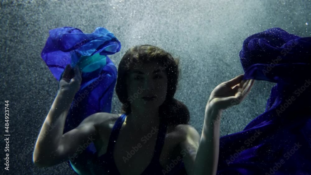 stunning and mysterious lady in blue silk dress is floating in deepness ...