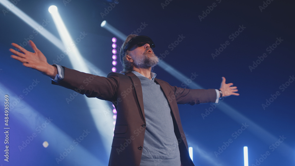Cheerful male host on stage spreading his arms and showing the audience ...