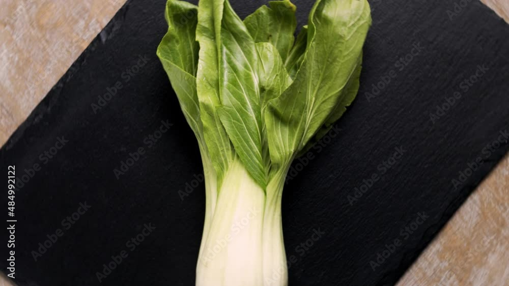 Pok choi cabbage on black slate, top view, table spin. Fresh leafy ...