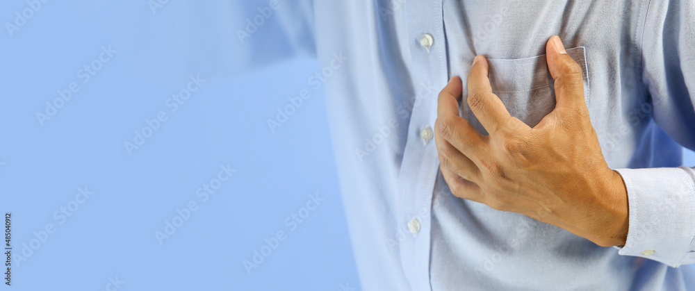 Hand squeezing the left chest pain on blue background concept of heart ...