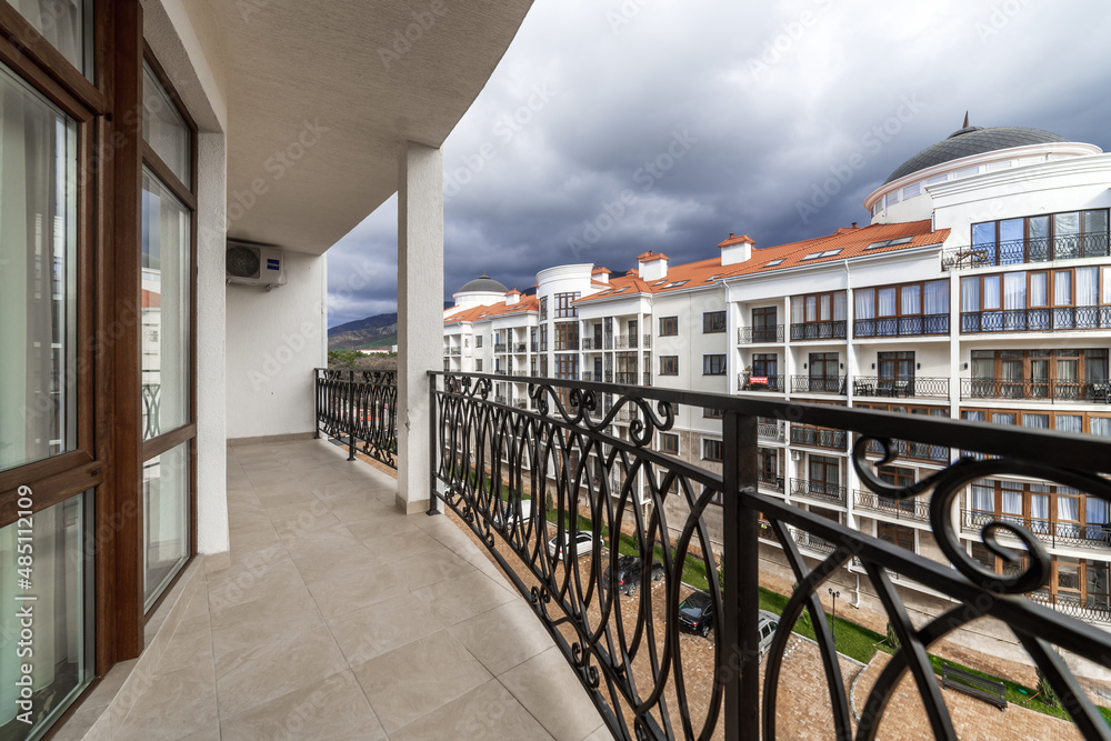 A wide curved balcony of a multi-storey building with metal black ...